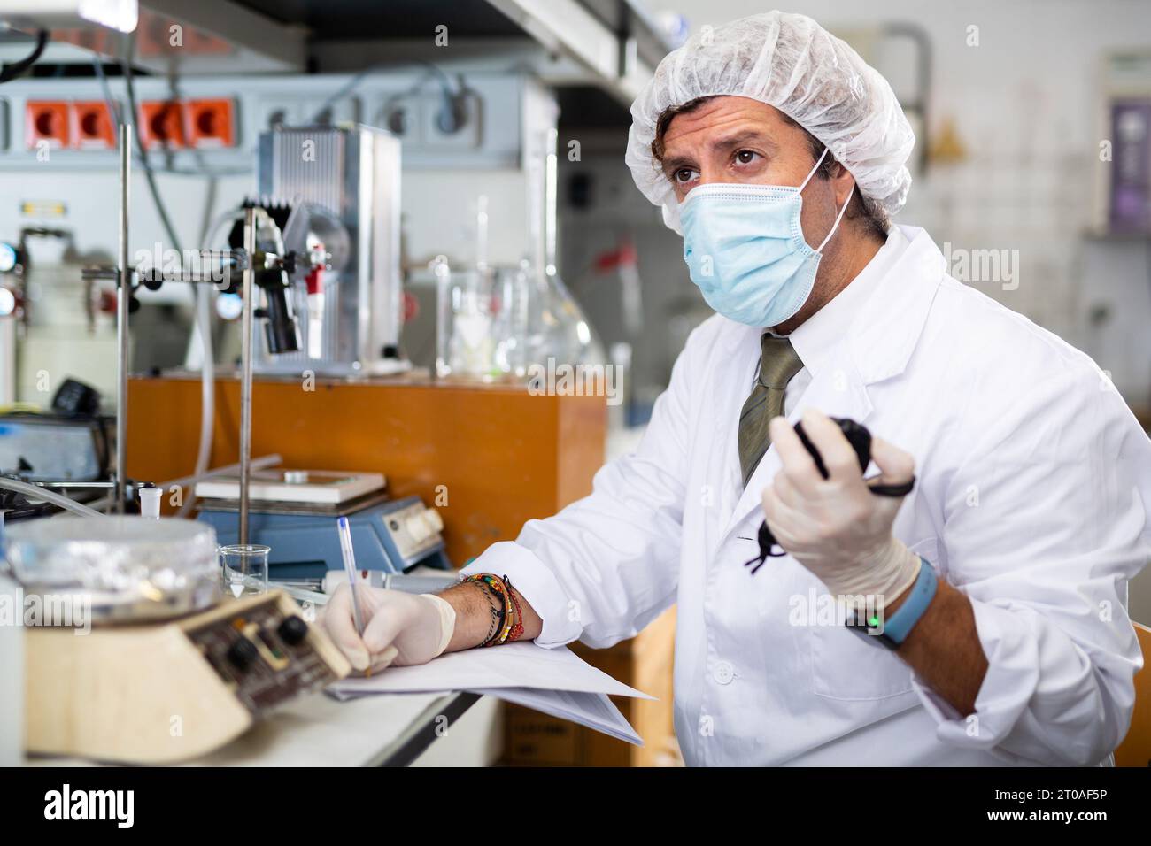 Male scientist engaged in research in chemical laboratory, noting ...