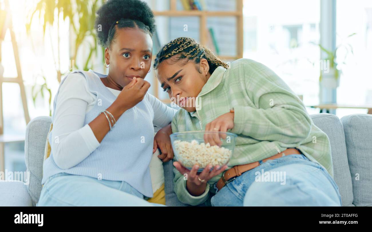 Scary, movie and friends on sofa in living room with popcorn, snack or ...