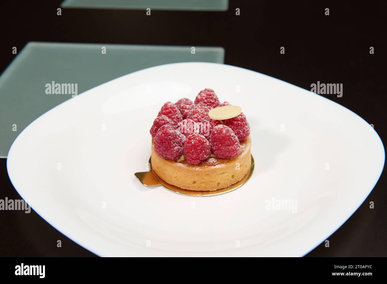 A sweet tartlet with raspberries on a white plate over wooden ...