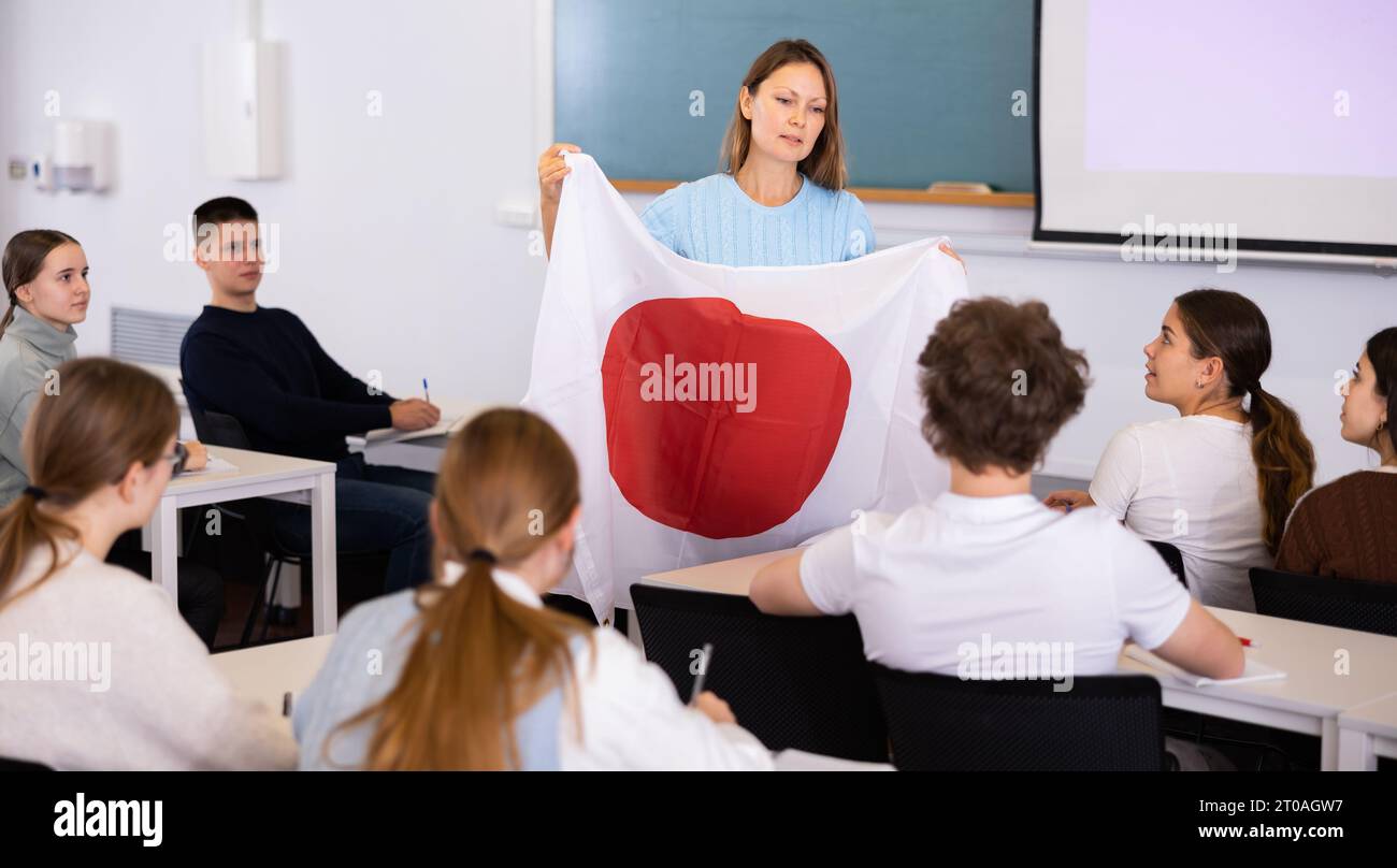 Adult female teacher showing students the flag of Japan Stock Photo - Alamy