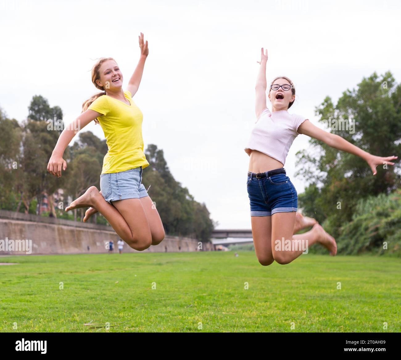 Two young barefoot girls jumping on grass Stock Photo - Alamy