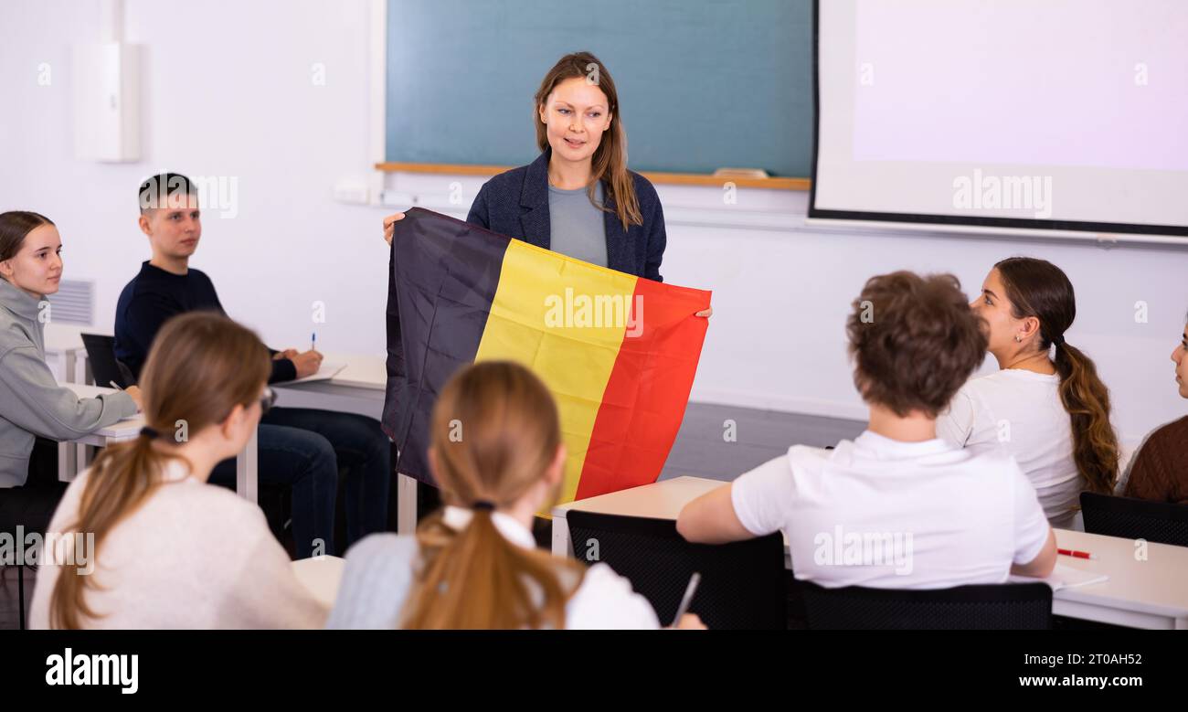 Teenage students sitting in class and listening carefully to female ...