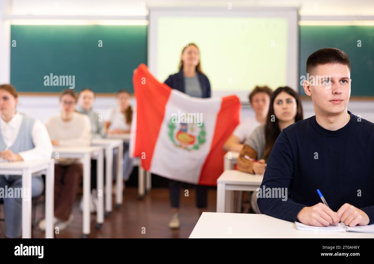 Teenage students in class and listening carefully to female teacher ...
