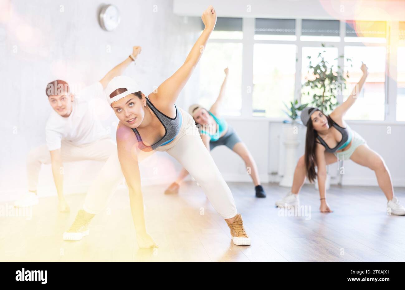 Portrait of positive teenager learning dynamic dance moves with group ...