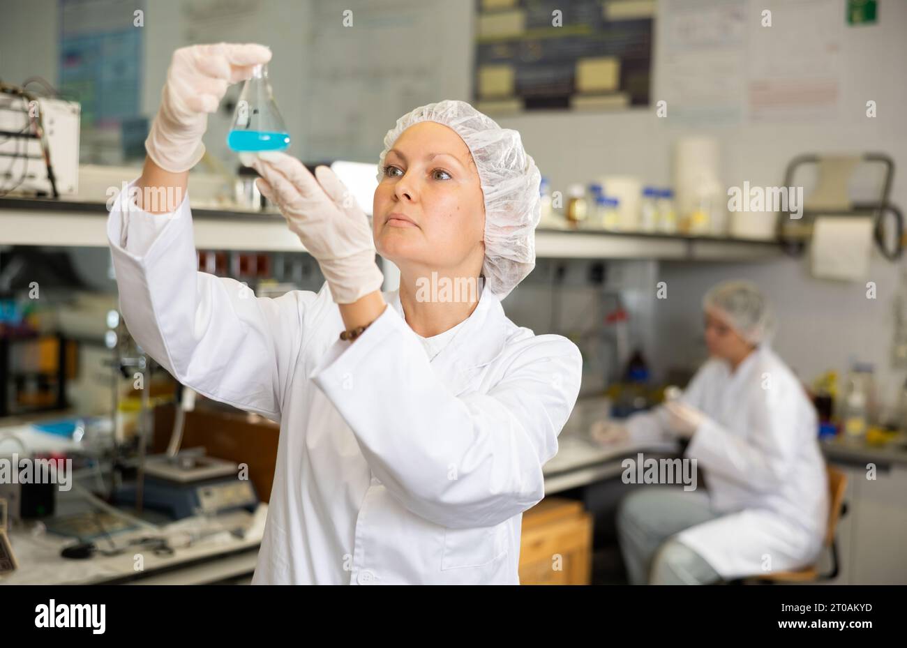 Efficient female lab technician working with reagents in test tubes ...