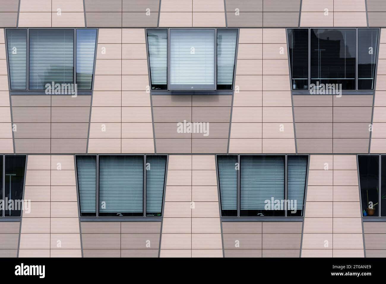 Beige wall of a modern building with trapezoidal windows. From the ...