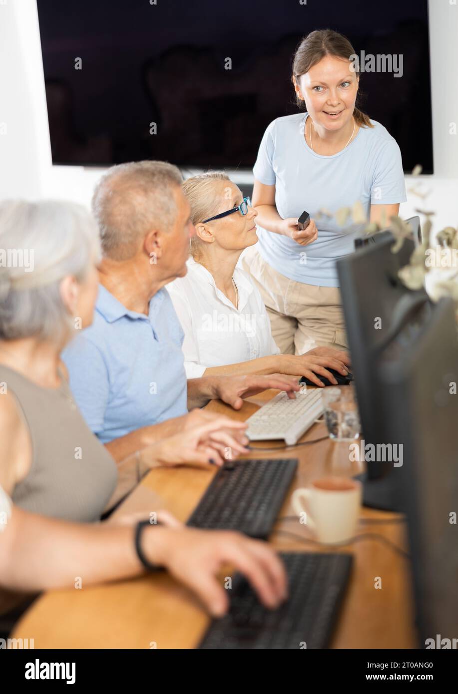 Woman teacher teaching elderly people how to use computer Stock Photo ...