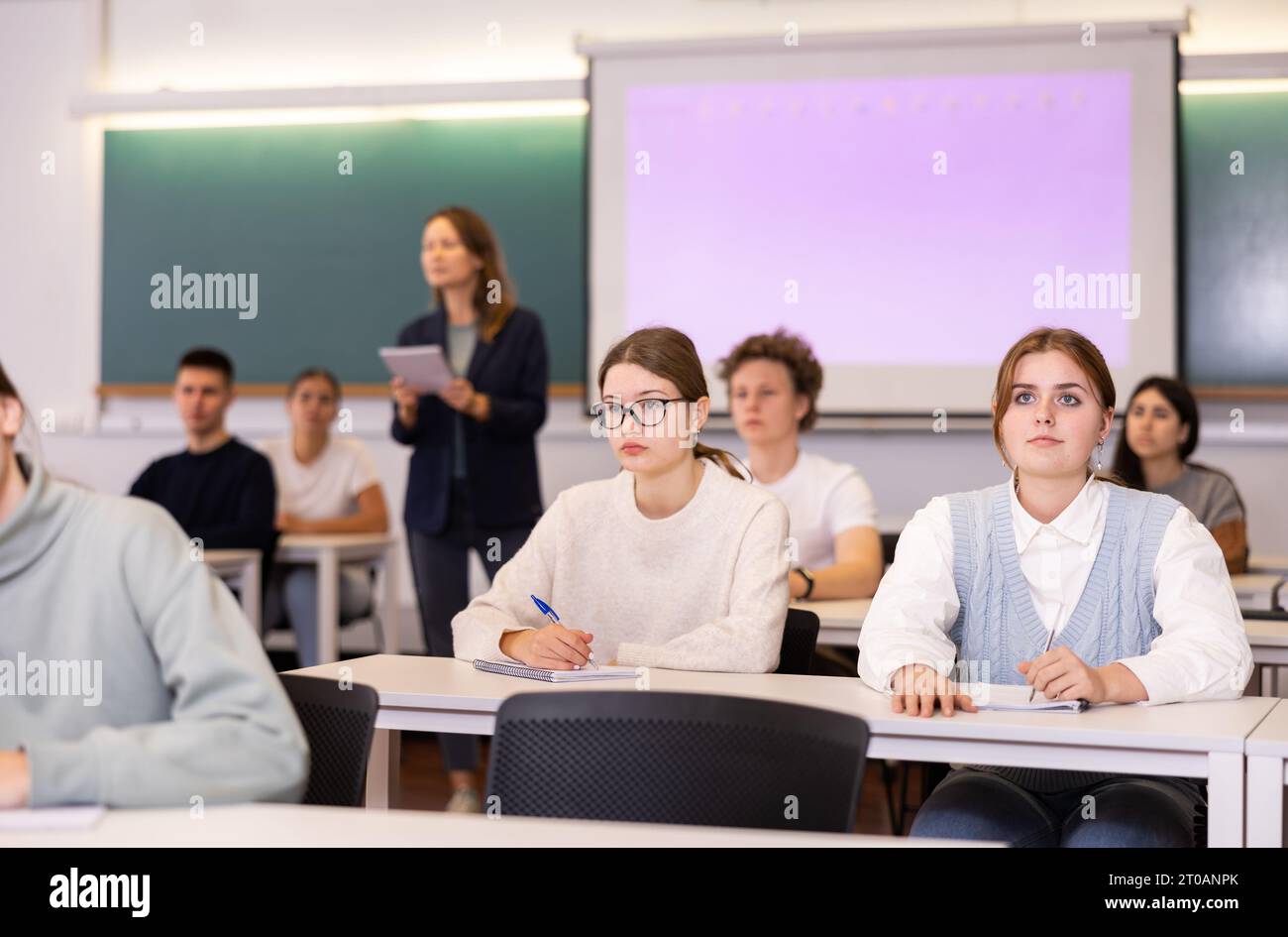 College students sit at desk and write in textbook Stock Photo - Alamy