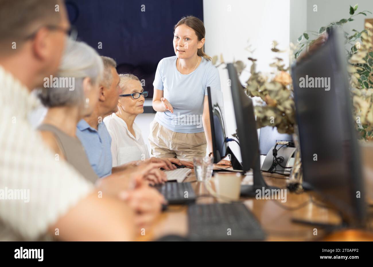 Woman teacher teaching elderly people how to use computer Stock Photo ...