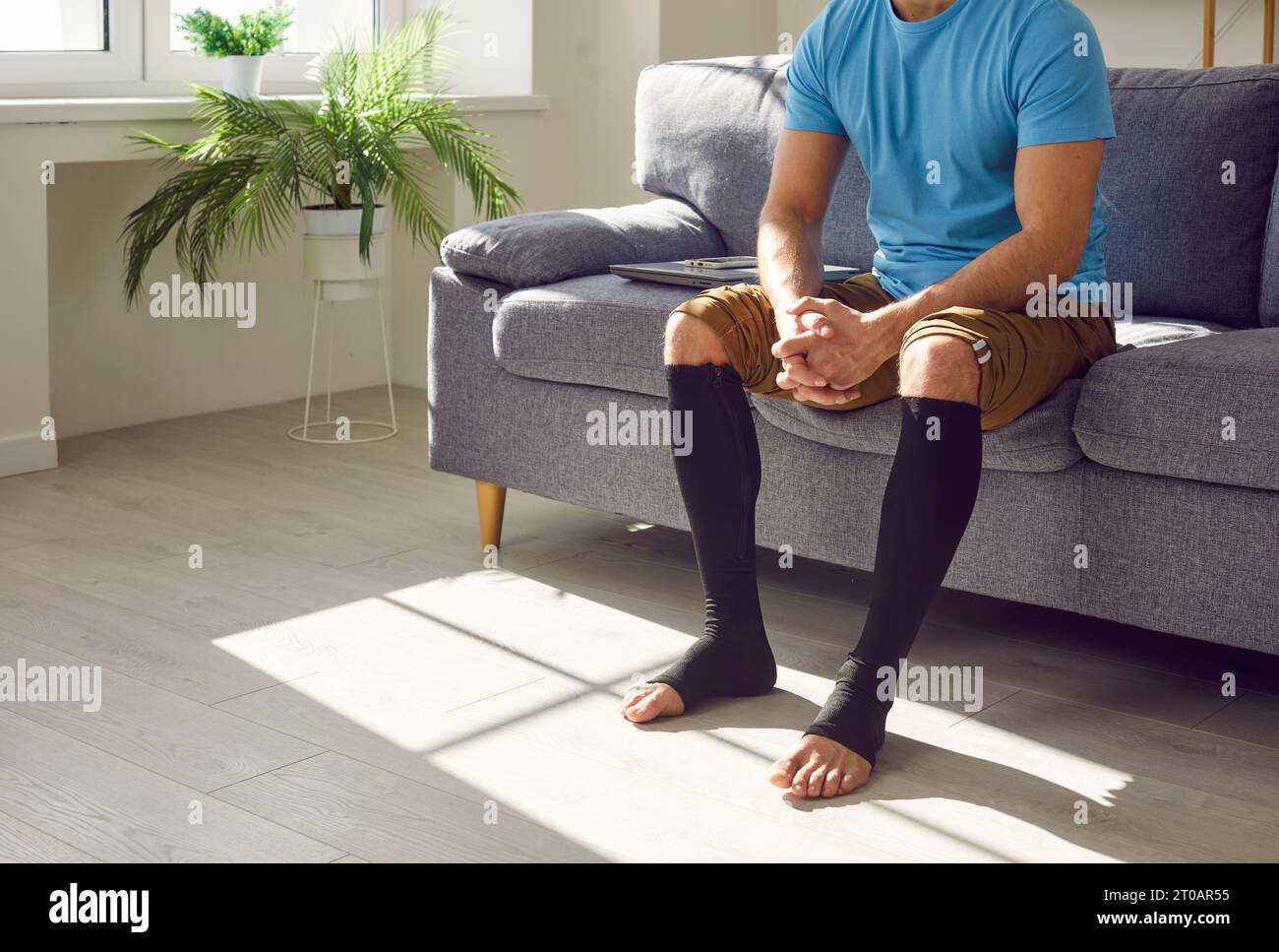 Man sitting on sofa in medical compression stockings on legs for the ...