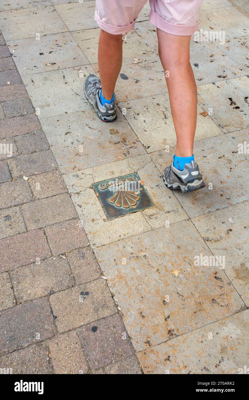 Pilgrim walking past a scallop shell marker in the Spanish Town of ...
