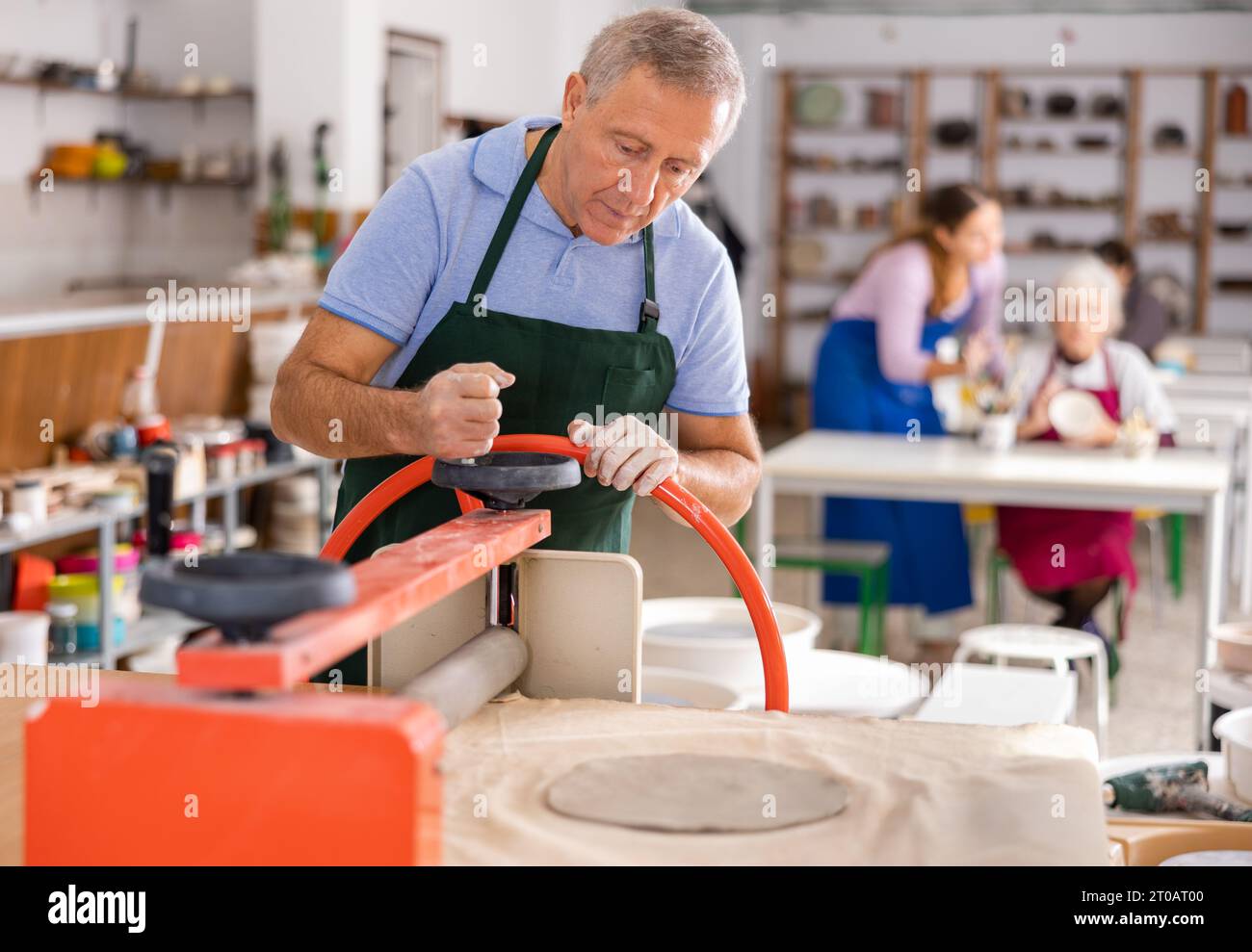 Old man rolling piece of clay on special machine - craft machine clay ...