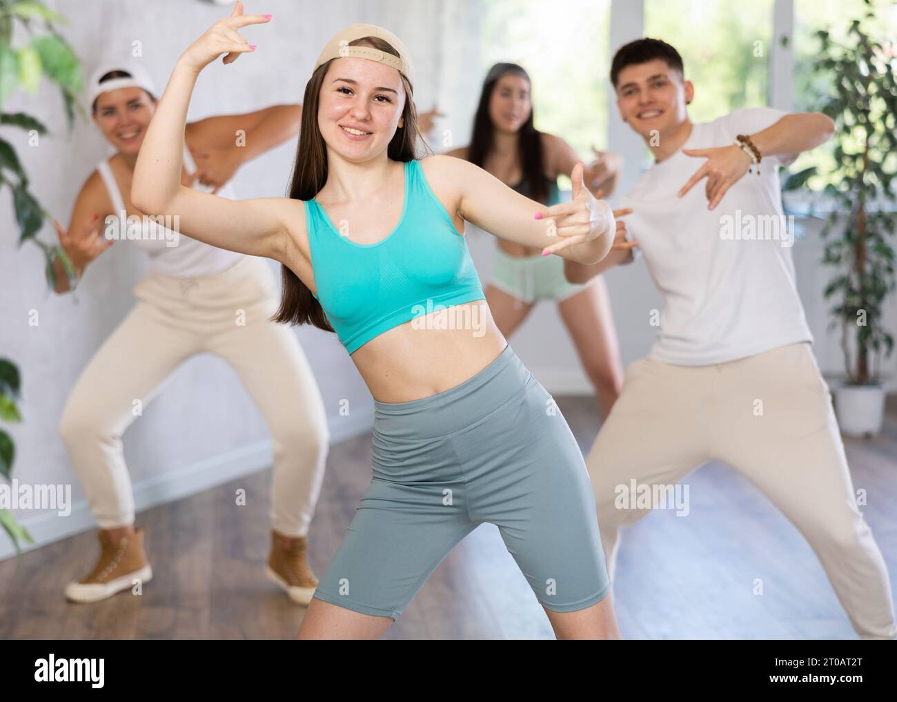 Teenage girl practicing hip-hop movements during group dance class ...