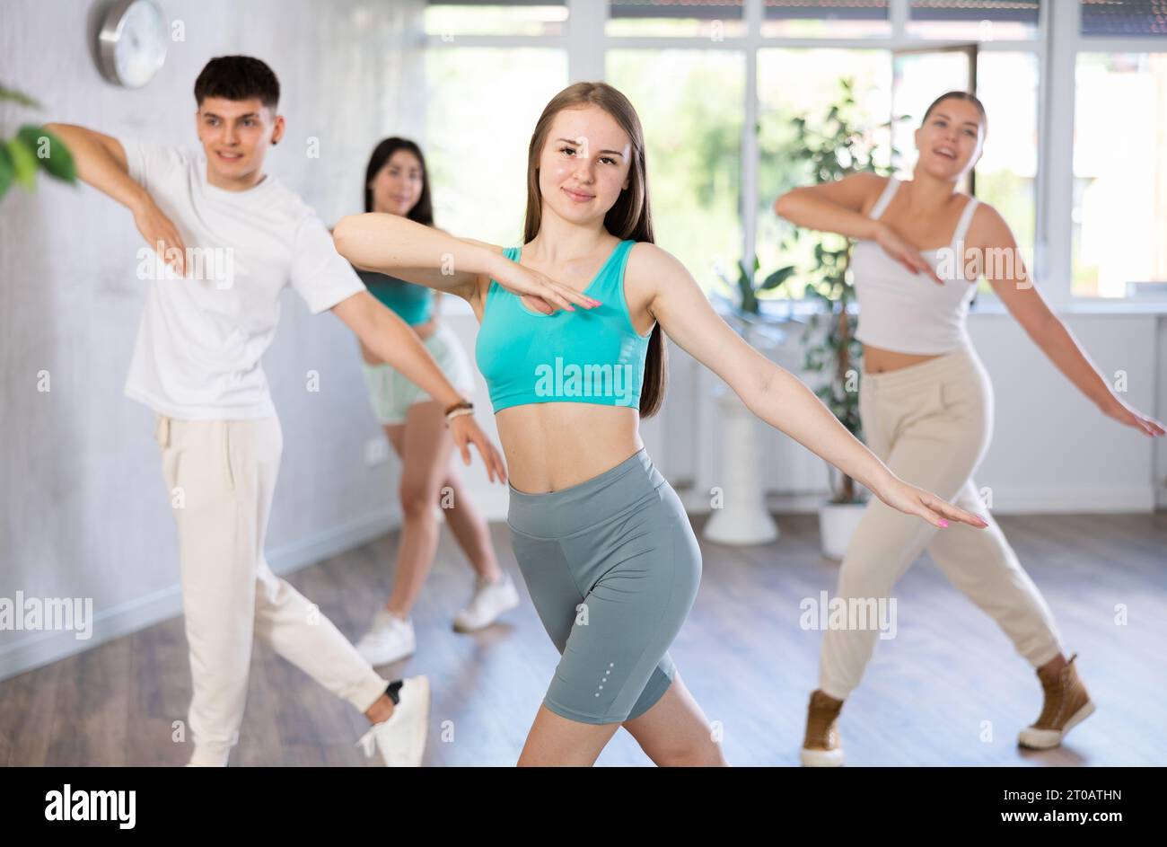 Cheerful teenage girl practicing energetic dance in choreography class ...