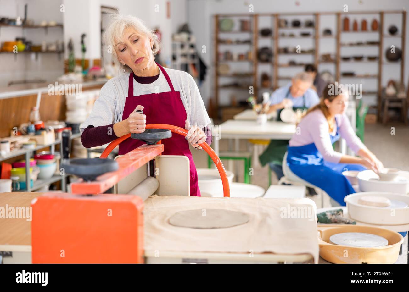 Woman rolling piece of clay on special mechanical machine - craft ...
