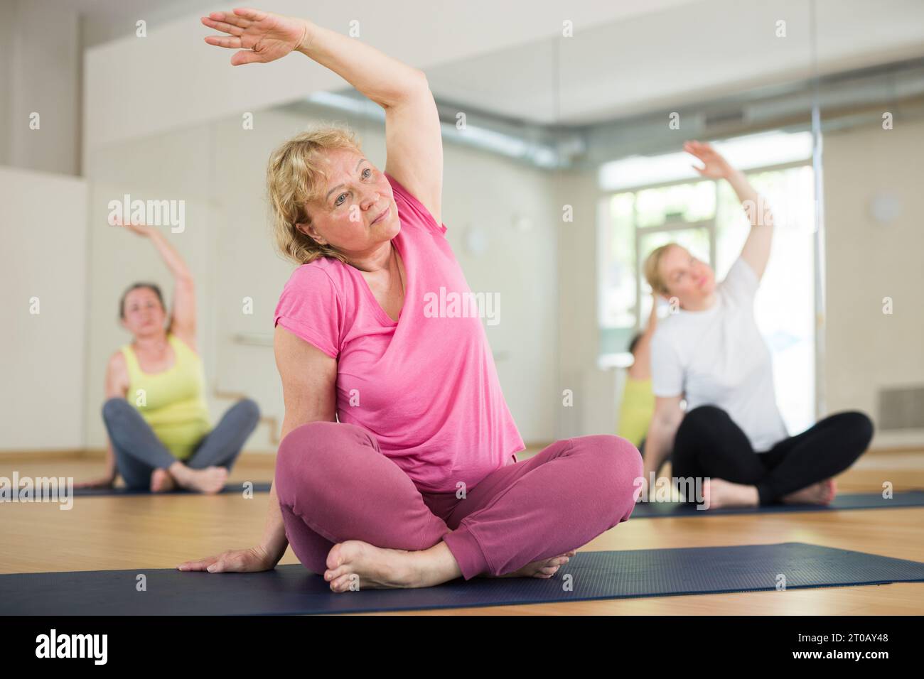 Women exercising during yoga class in fitness center - vakrasana pose ...