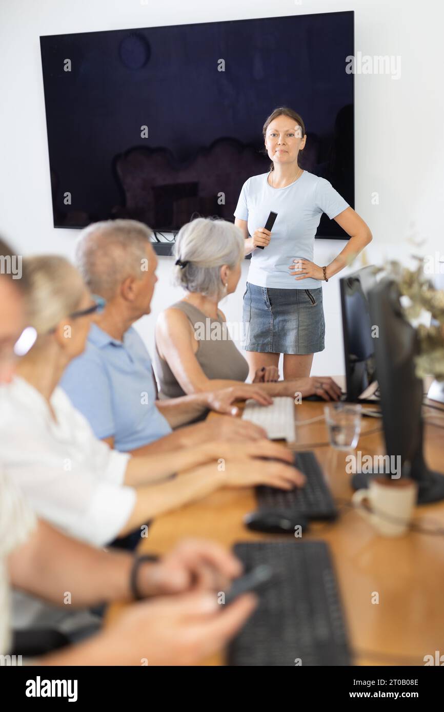 Woman teacher teaching elderly people how to use computer Stock Photo ...