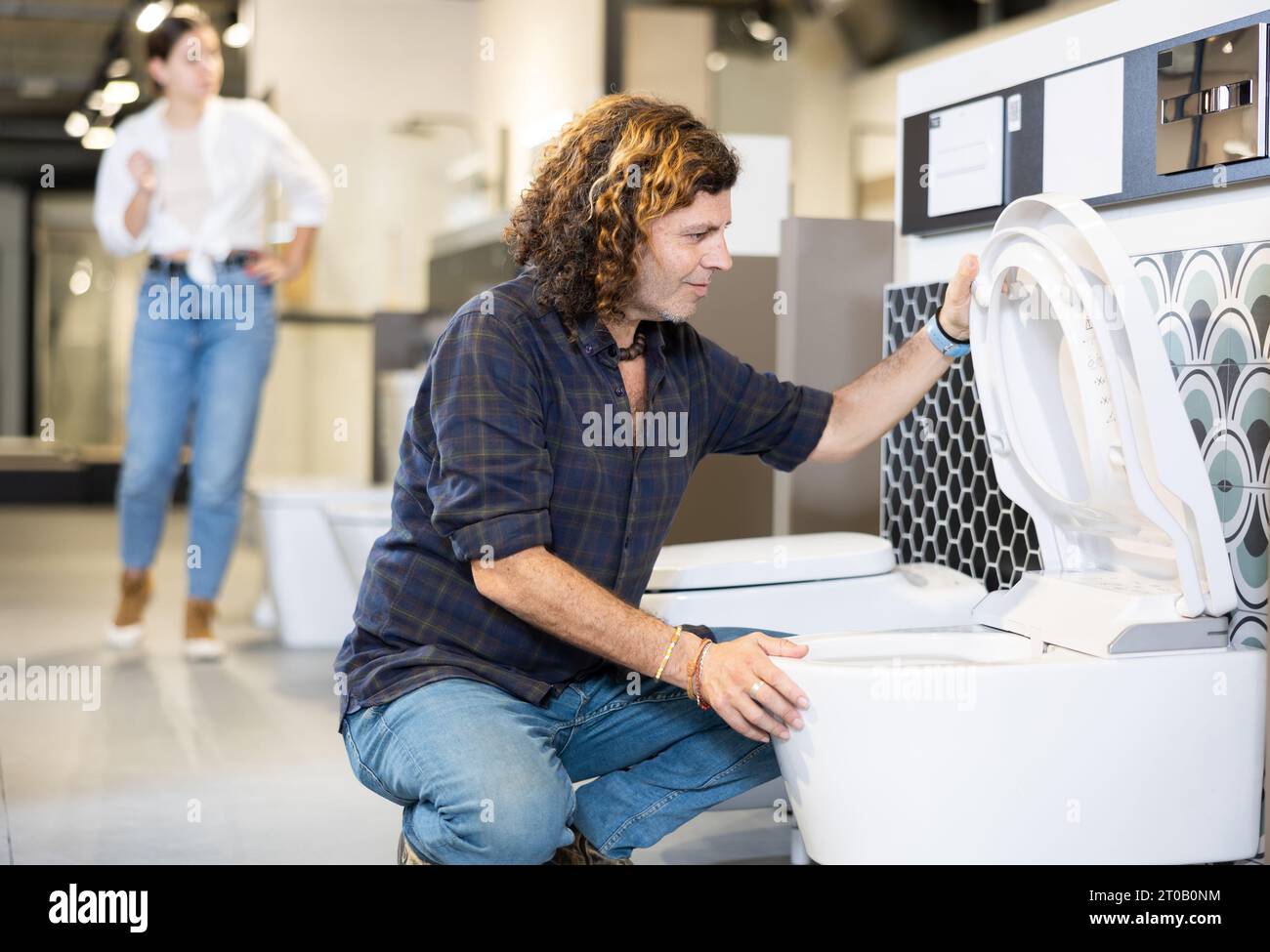 in plumbing department, male buyer checks for defects of toilet before ...