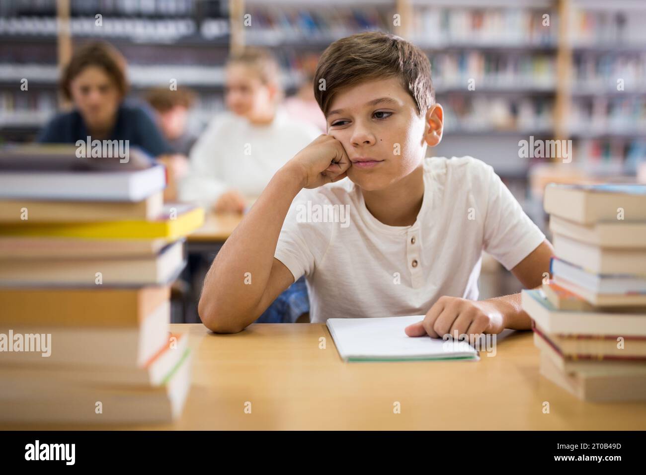 Bored young boy in library Stock Photo - Alamy