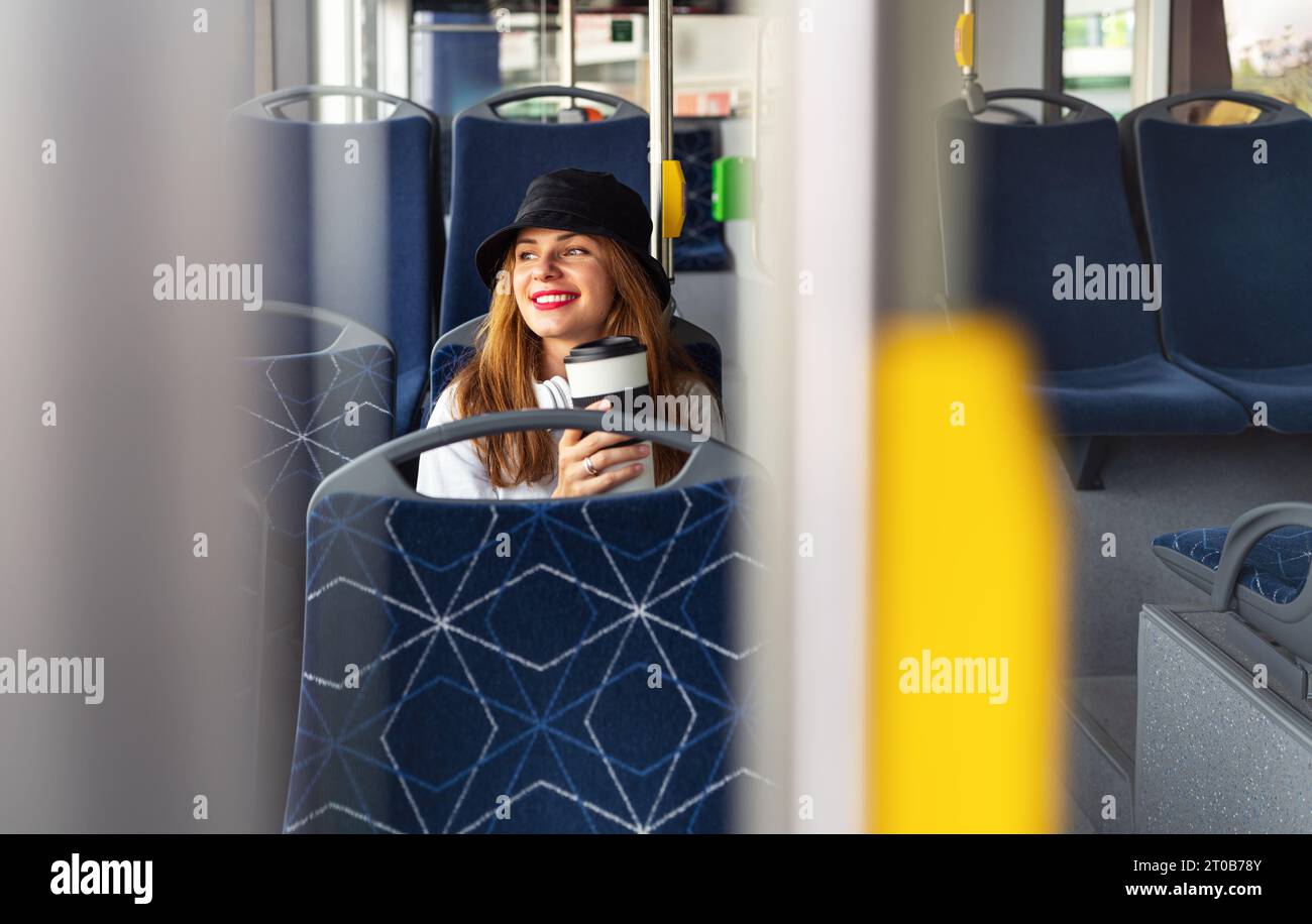 Young urban woman passenger sitting travels by city electric bus ...