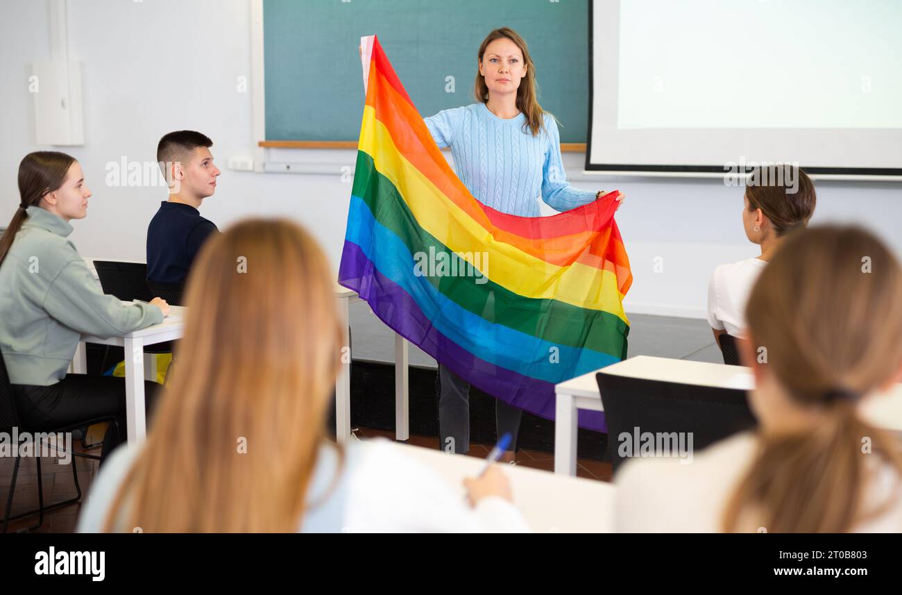 Adult female teacher showing LGBT flag to students Stock Photo - Alamy