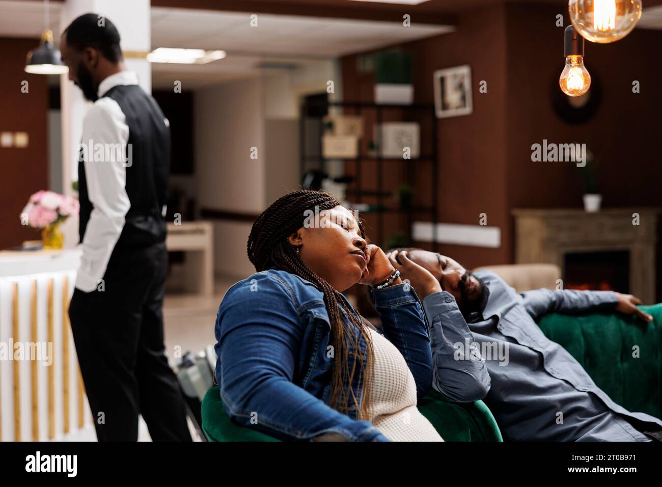 Tired exhausted African American couple fall asleep on couch in hotel ...