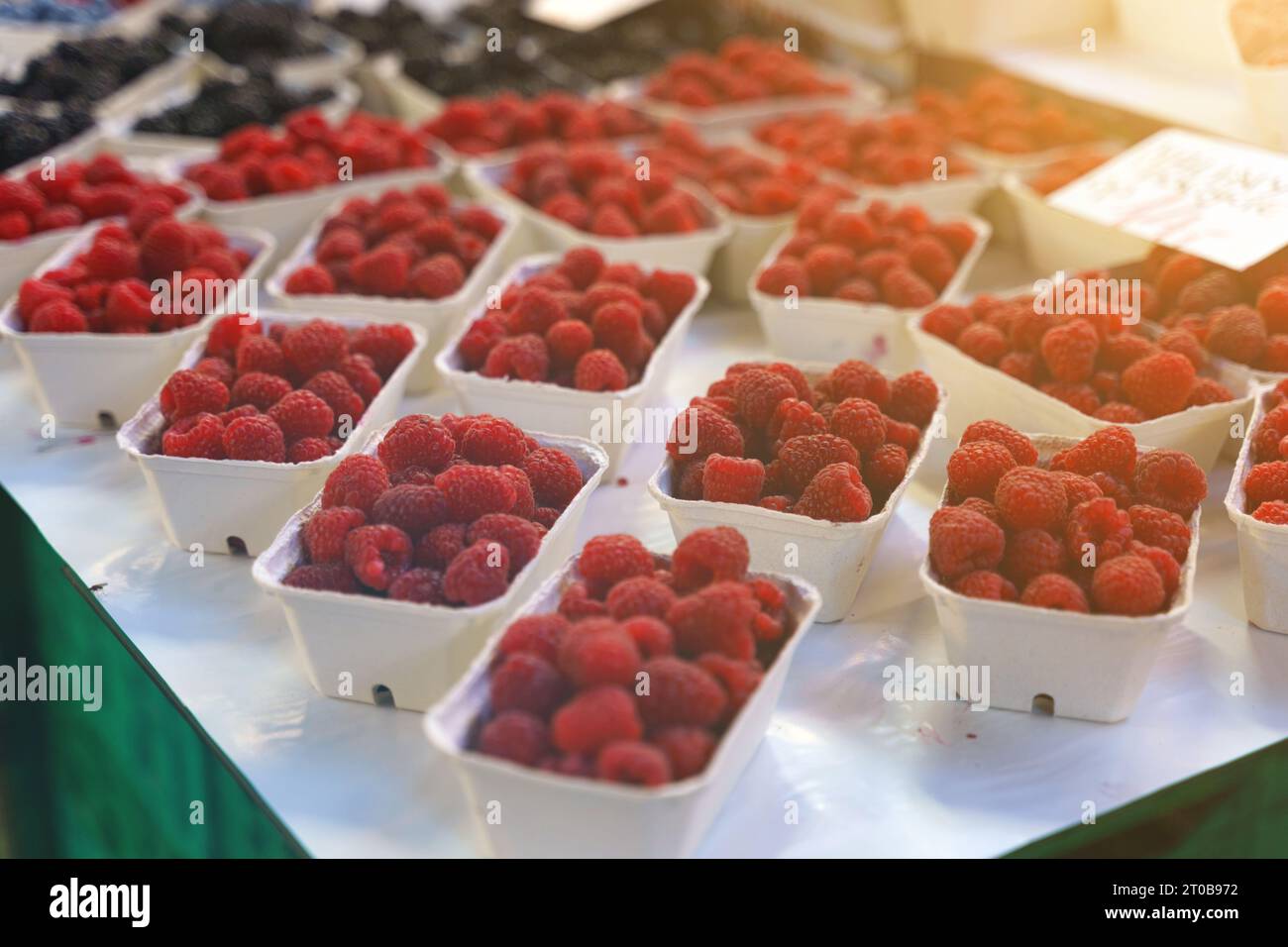 Raspberries in plastic containers on a market counter. Vegetable market ...