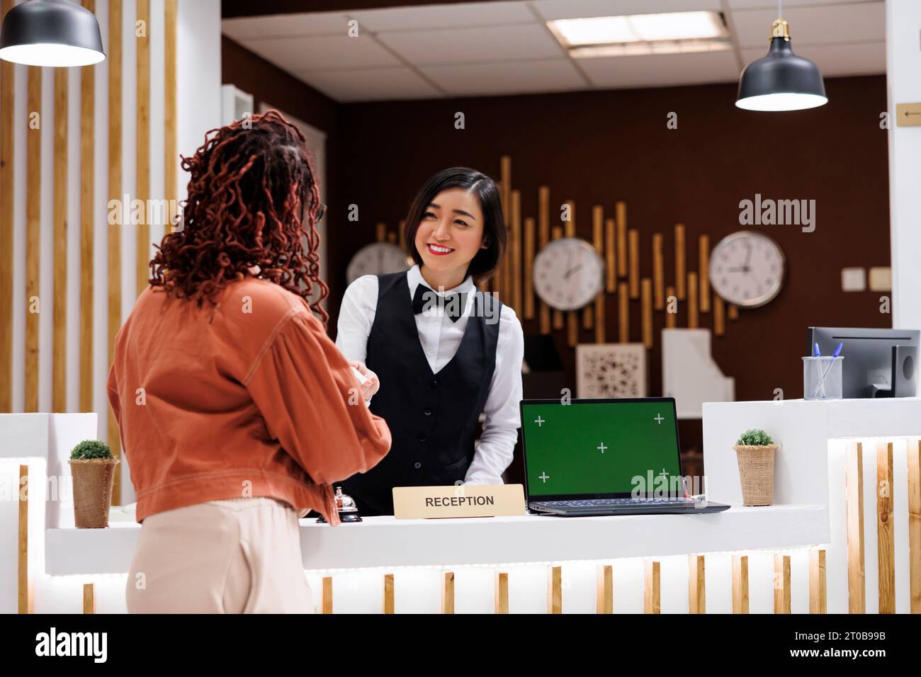 Hotel staff giving access key card to guest, having laptop with ...