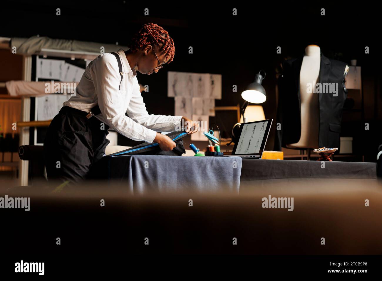 Hip level shot of suitmaker checking length size of unfinished custom ...