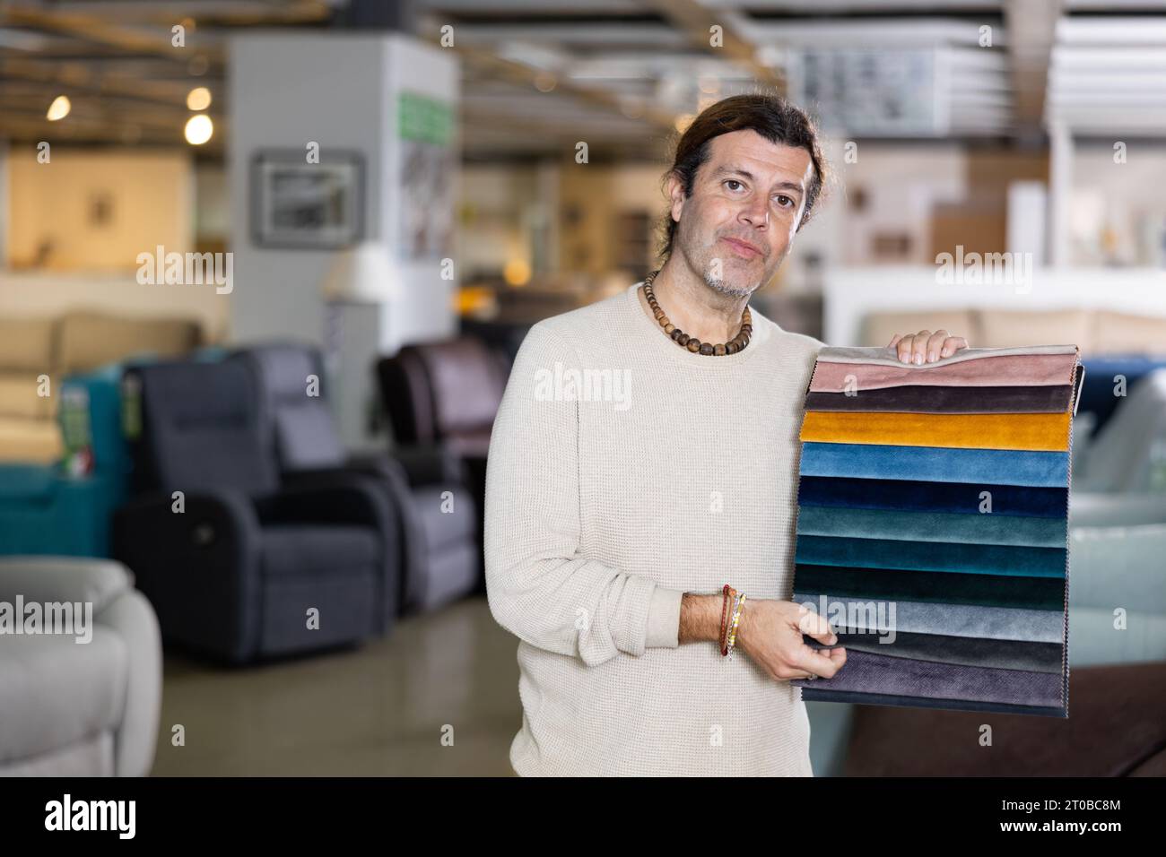 Male furniture salesman showing different fabric samples in furniture ...