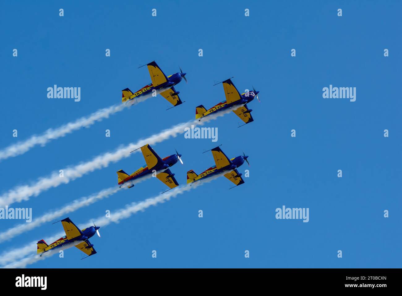 Four small airplanes flying in perfect formation, emitting smoke trails ...