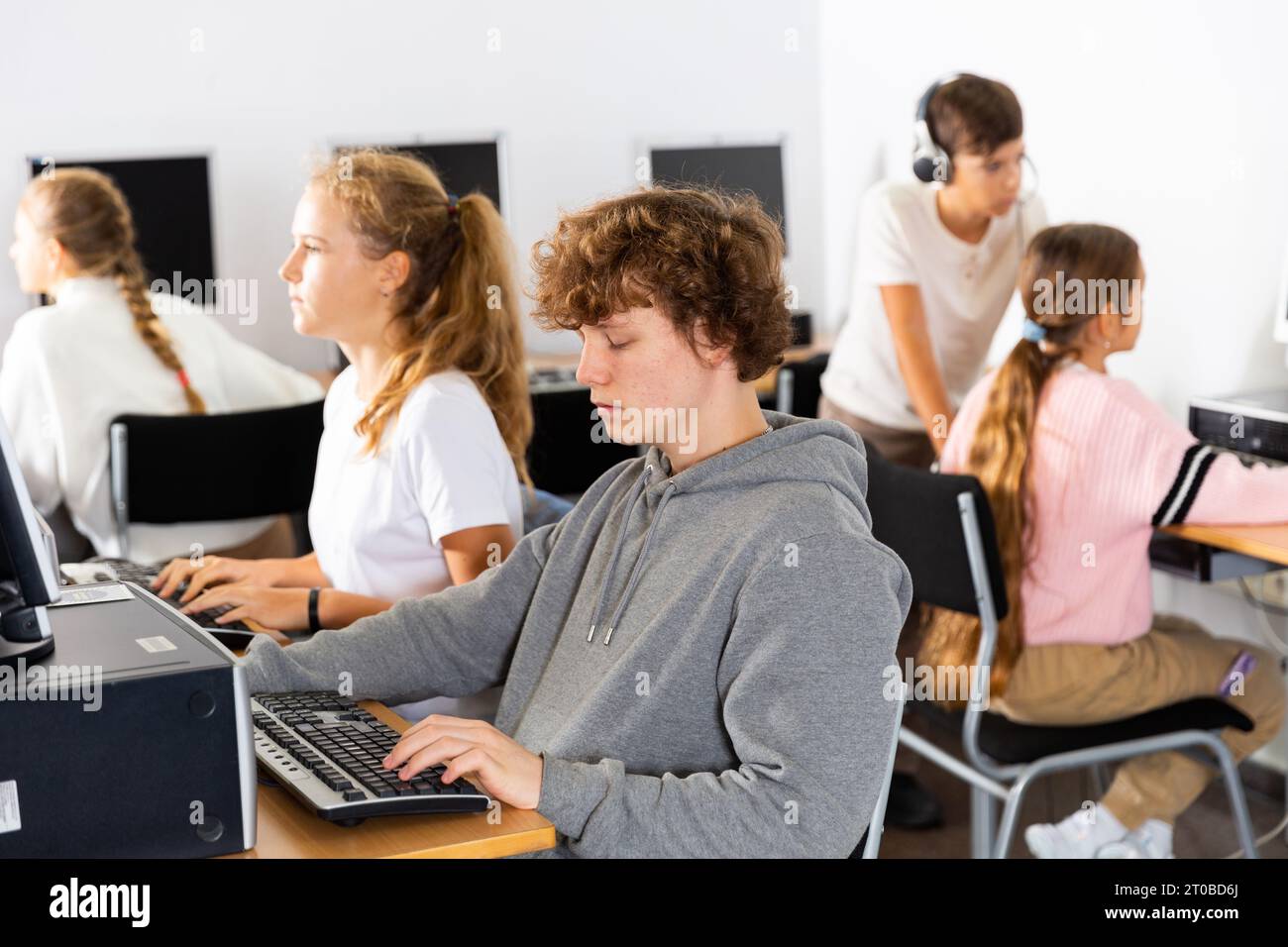 Pupils using computers at lesson, teacher teaching them in class room ...