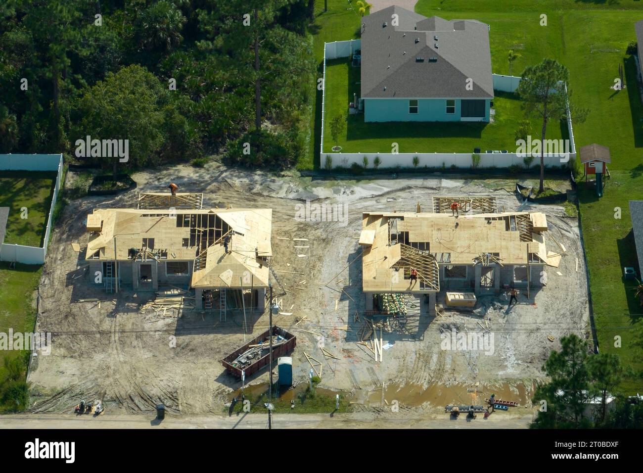 Aerial view of builders working on unfinished residential house with wooden roof frame structure ...