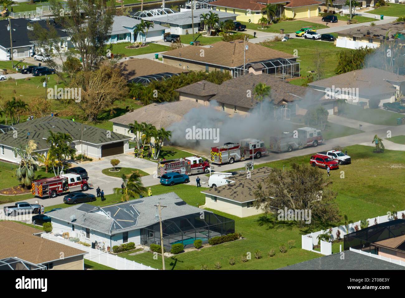 Aerial view of house on fire and firefighters extinguishing flames ...