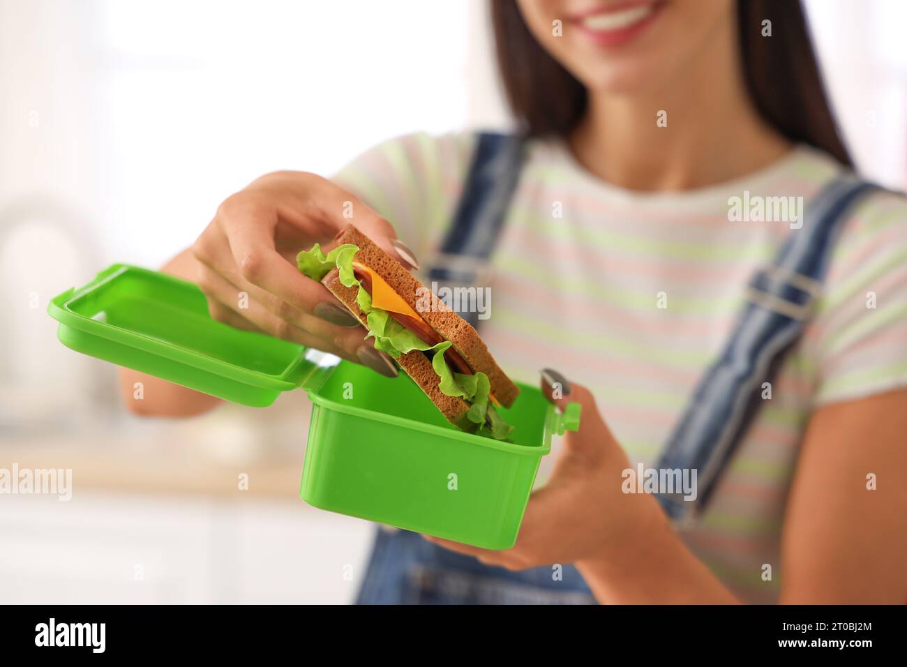 Young woman putting sandwich in school lunchbox at home Stock Photo - Alamy