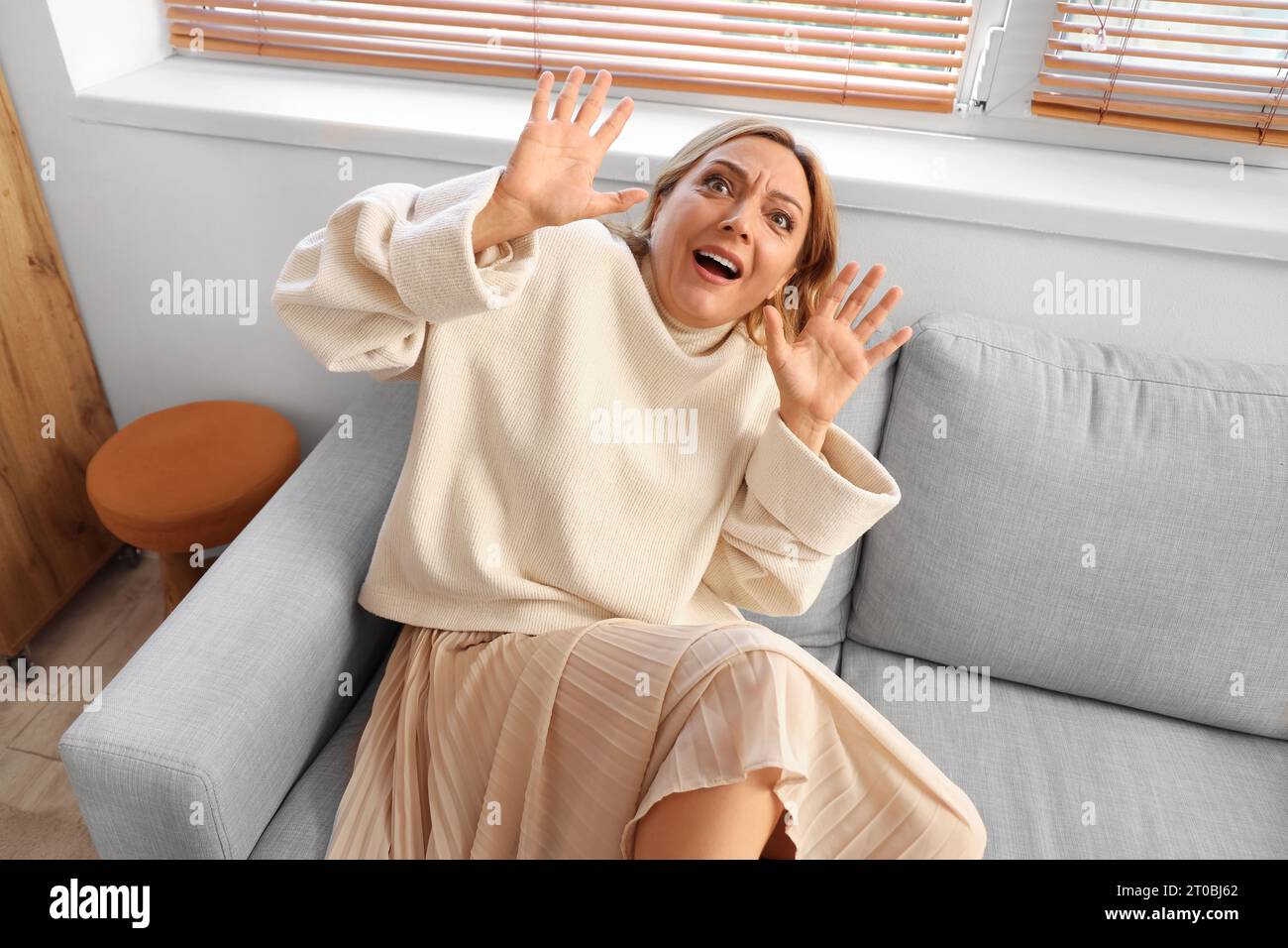 Scared mature woman sitting on sofa at home Stock Photo - Alamy