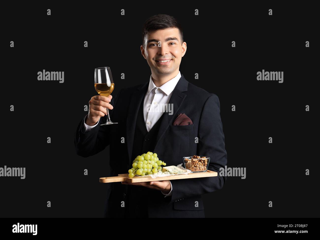 Young sommelier with glass of wine and snacks on black background Stock ...