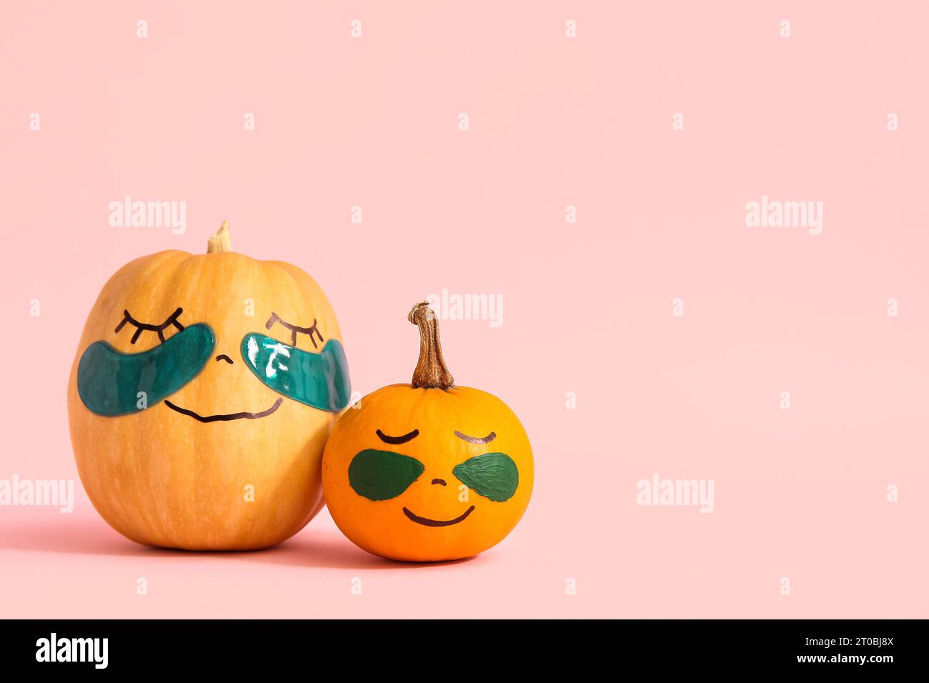 Pumpkins with drawn faces and under-eye patches on pink background ...