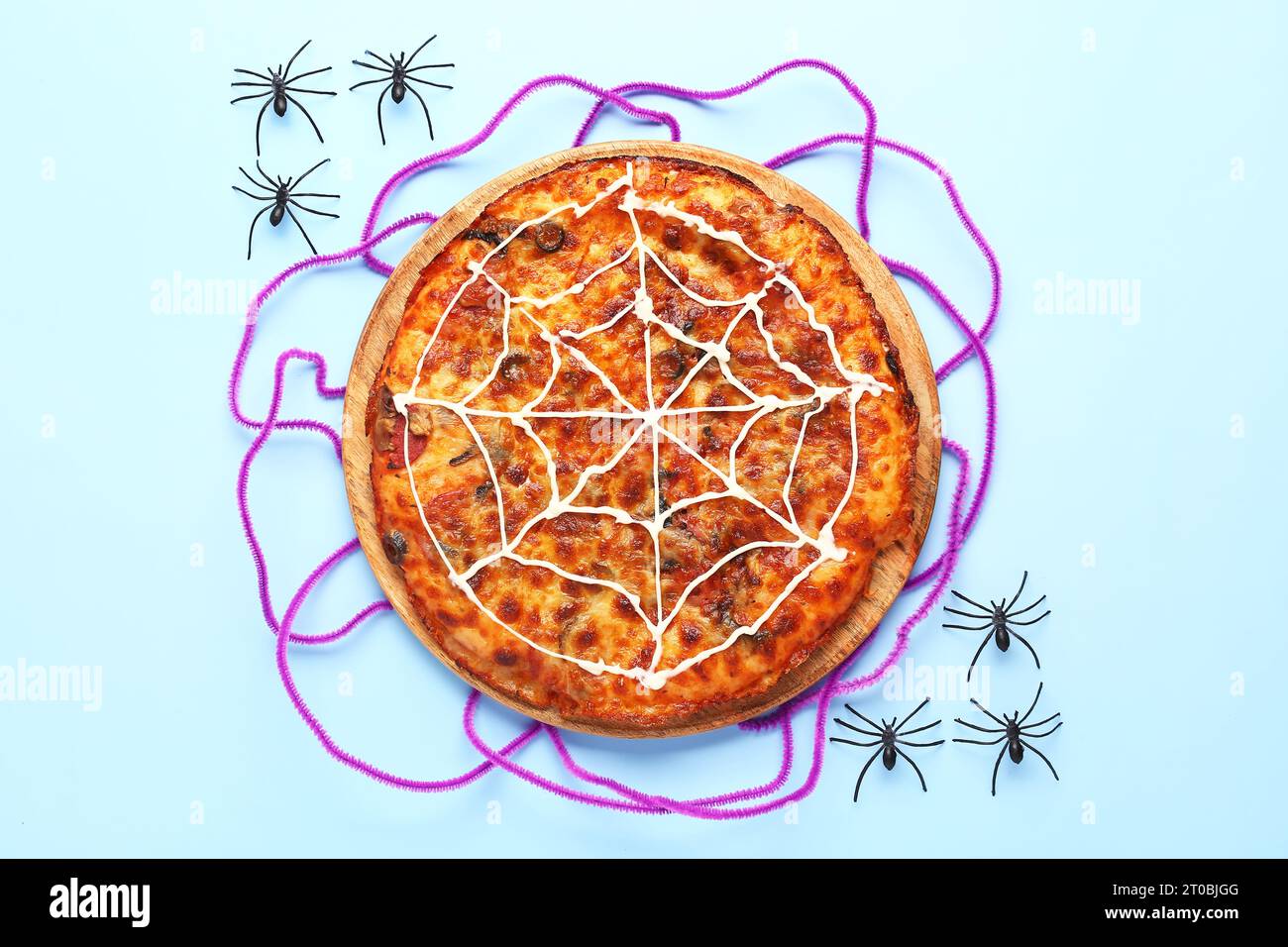 Wooden board with tasty pizza and spiders for Halloween party on blue ...