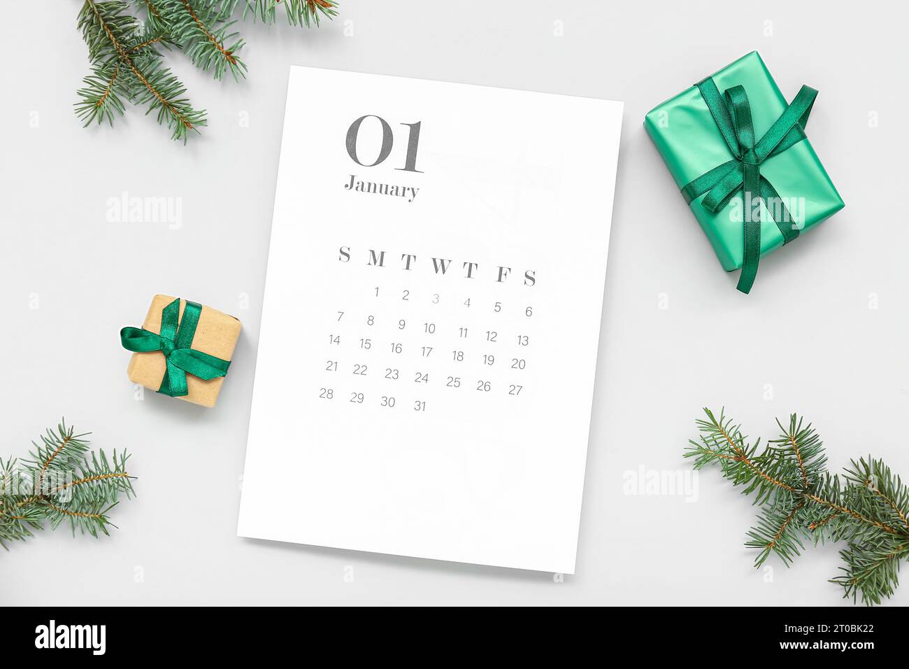 Paper calendar for January 1 with gift boxes and fir branches on grey ...
