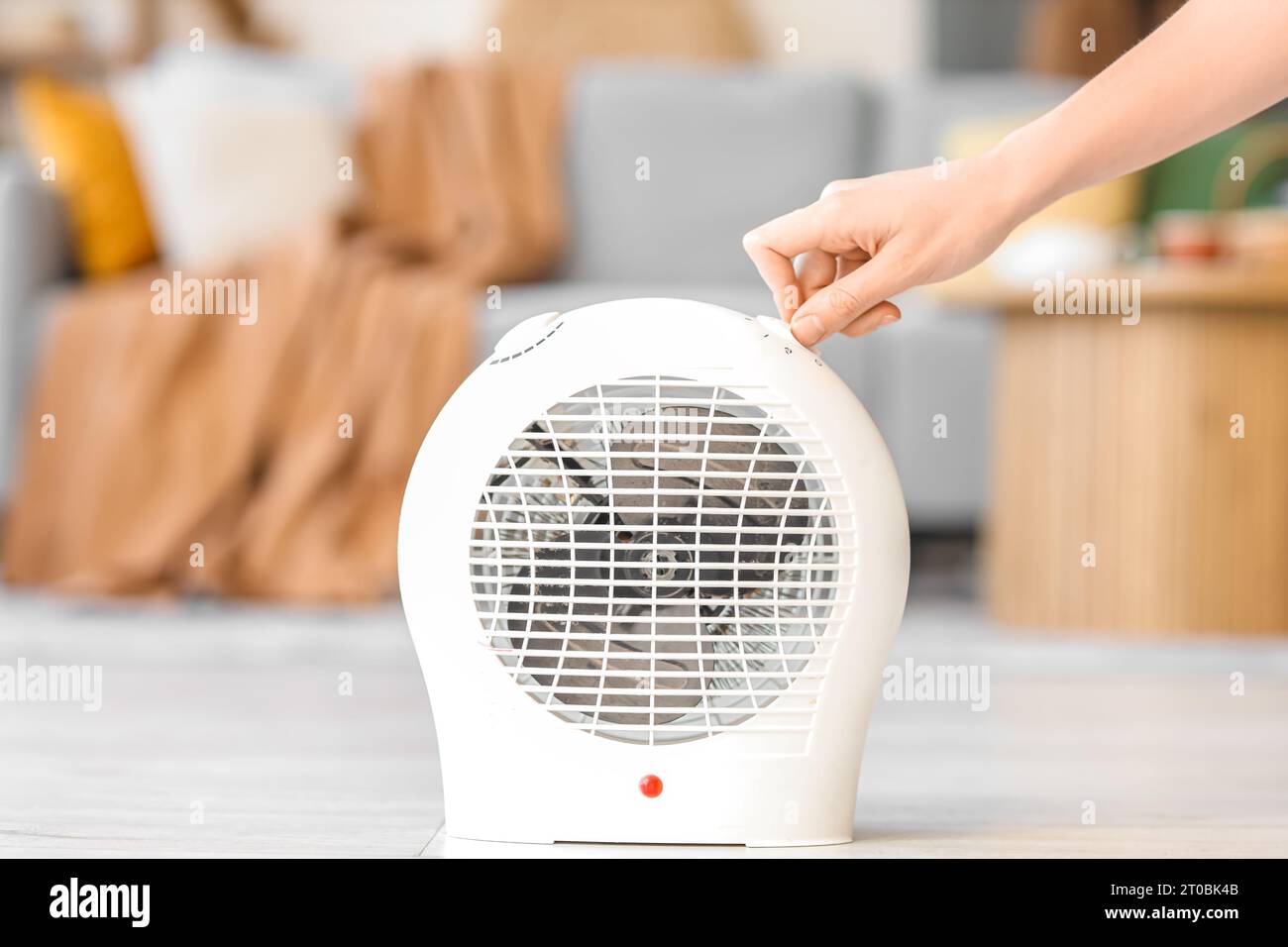 Woman turning on electric fan heater at home, closeup Stock Photo - Alamy