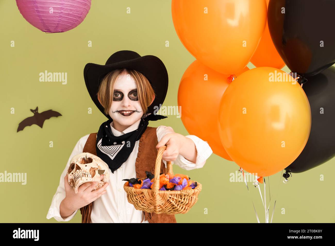 Little boy dressed for Halloween with candies and balloons near green ...