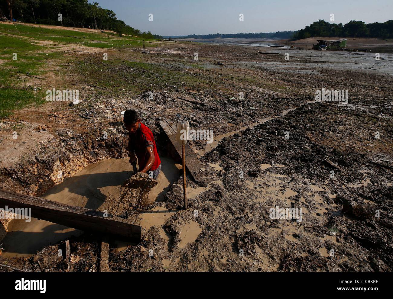 A man digs into the dry bed of Puraquequara lake to obtain water amid a ...
