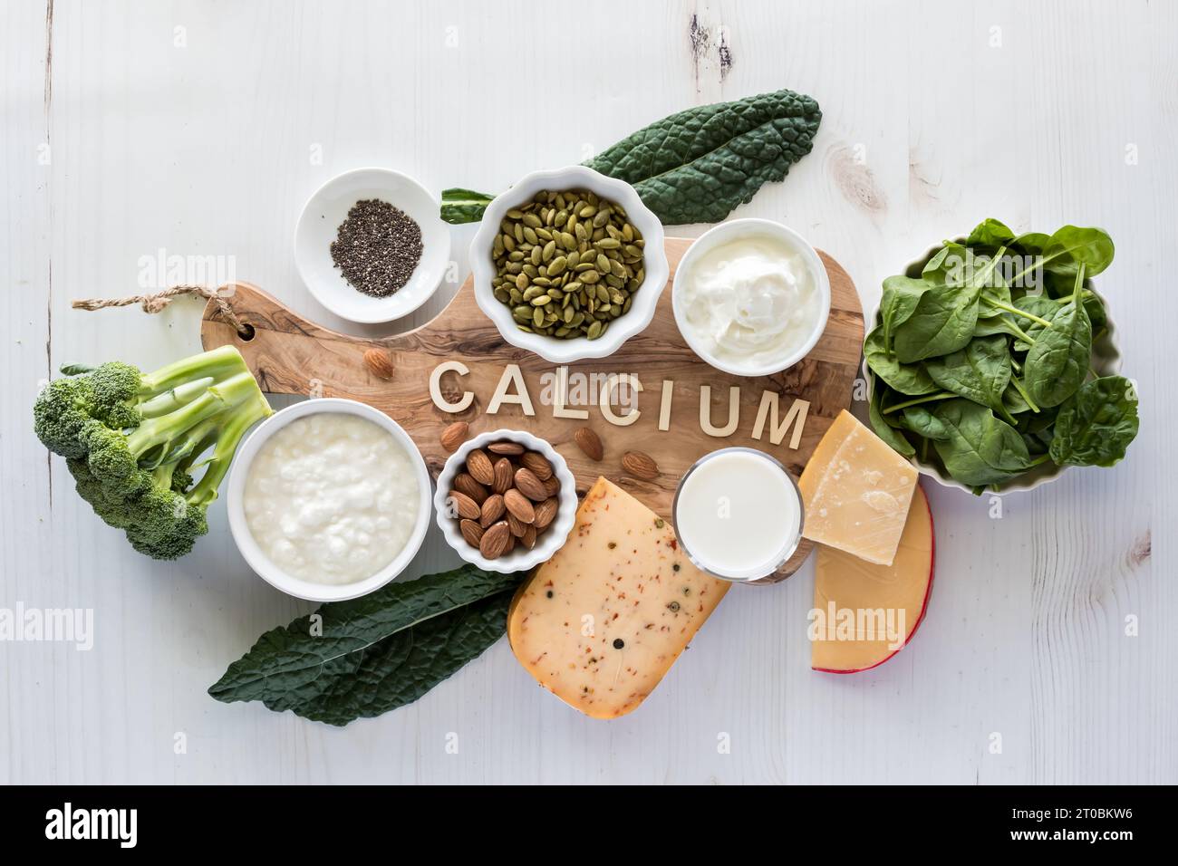 A group of calcium rich foods on a wooden board, against a light ...