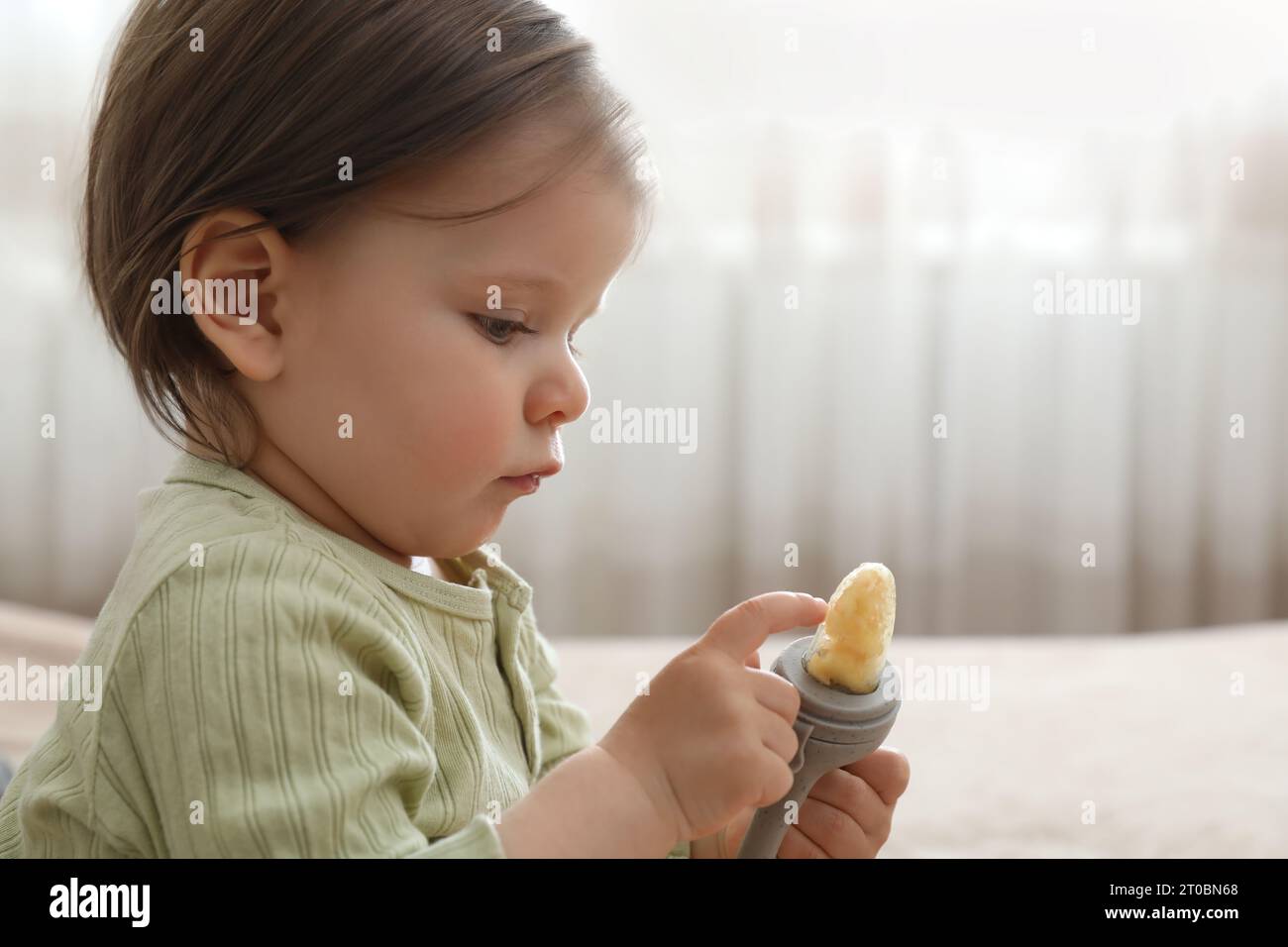 Cute baby girl with nibbler at home Stock Photo - Alamy