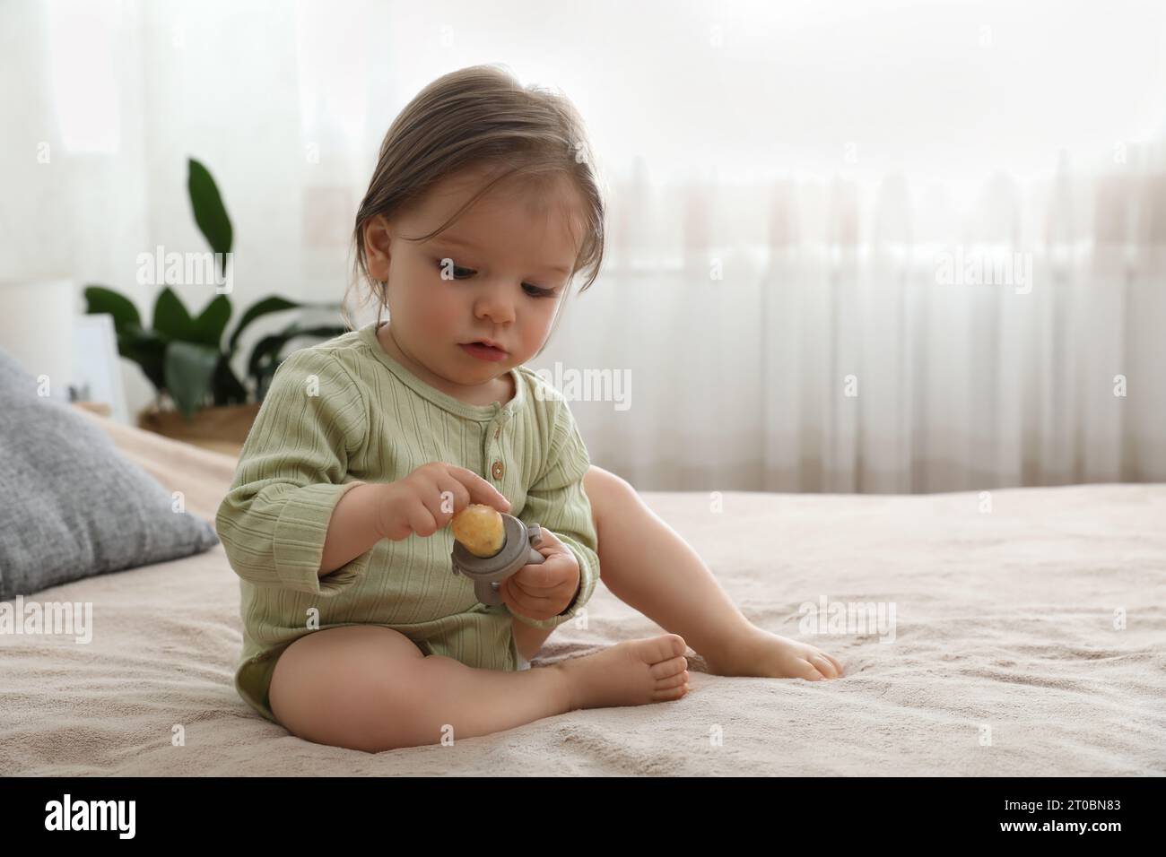 Cute baby girl with nibbler on bed at home. Space for text Stock Photo ...