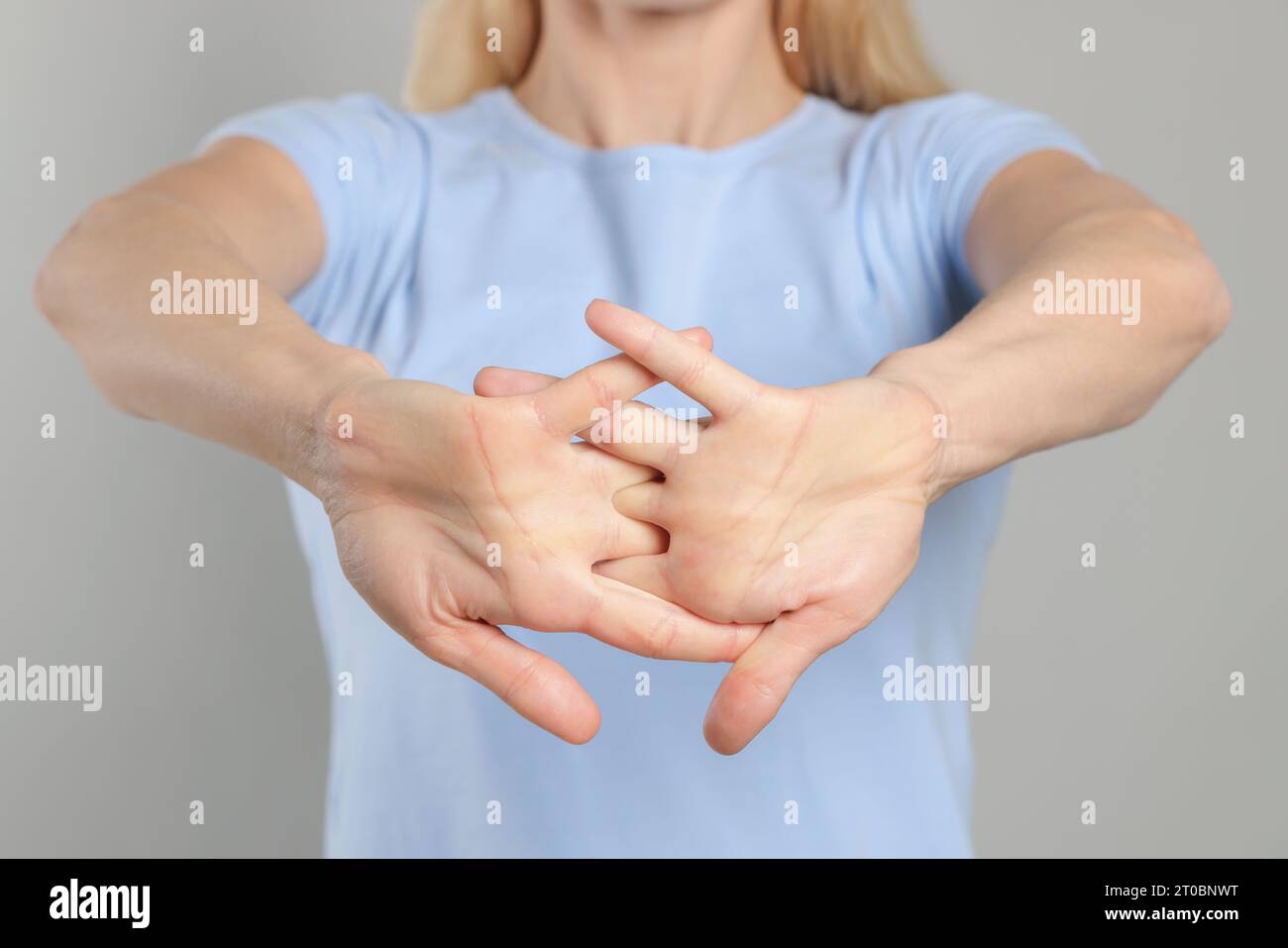 Woman cracking her knuckles on light grey background, closeup. Bad ...
