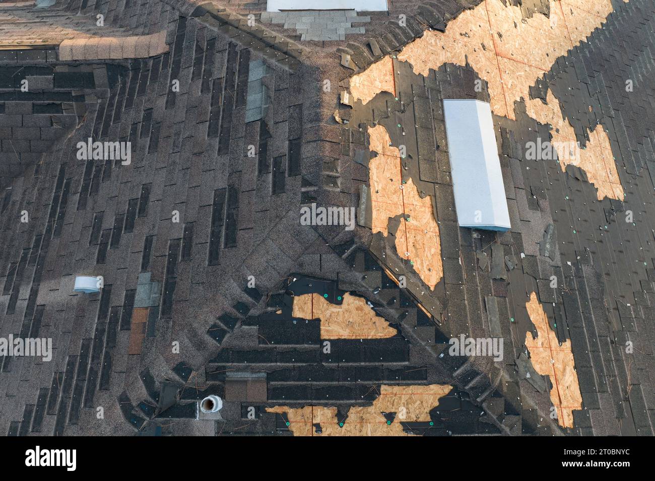 Wind damaged house roof with missing asphalt shingles after hurricane ...