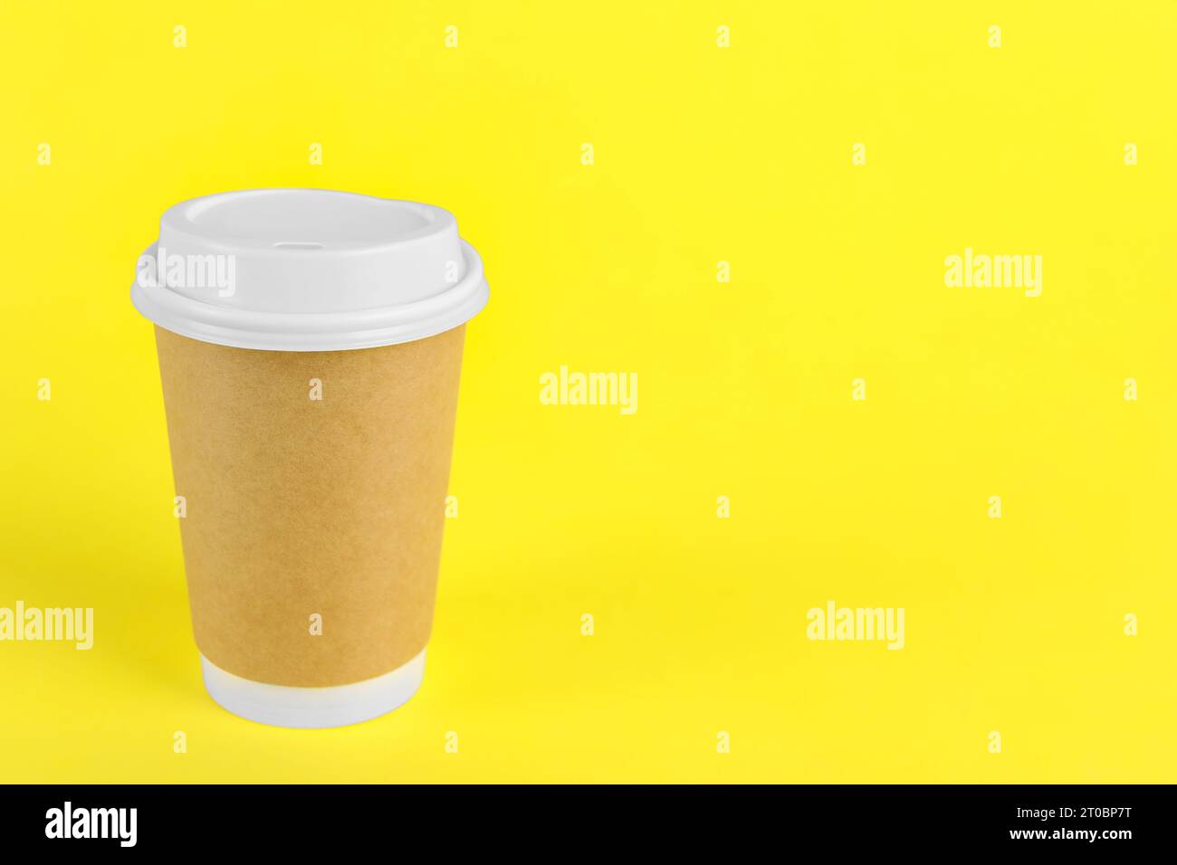 Paper cup with plastic lid on yellow background, space for text. Coffee ...