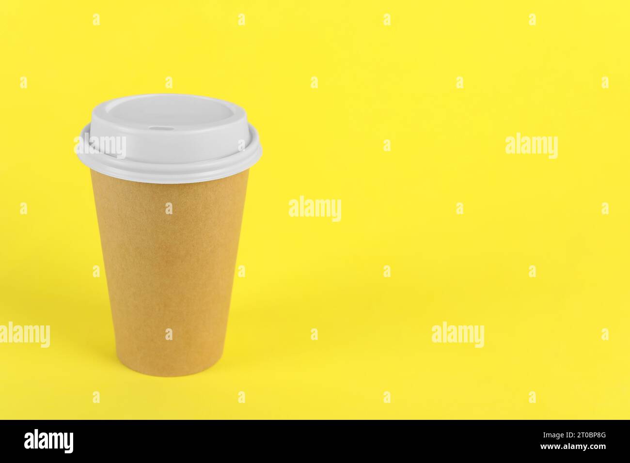 Paper cup with plastic lid on yellow background, space for text. Coffee ...